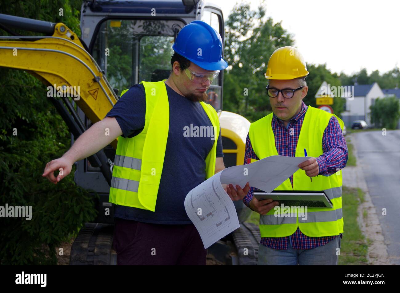 Engineer and worker on construction site with excavator in the ...