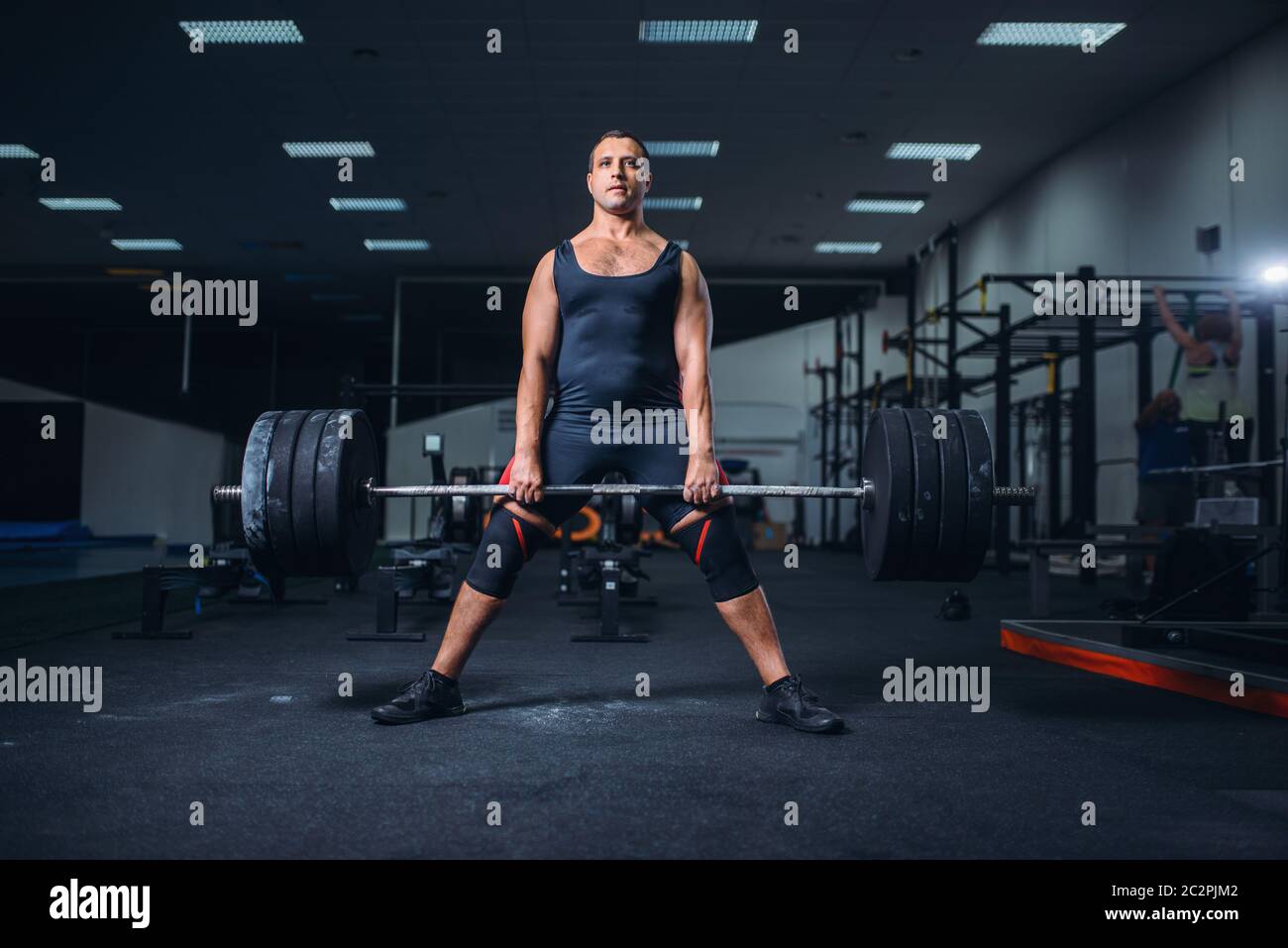 Strong male powerlifter keeps the weight of heavy barbell in gym ...