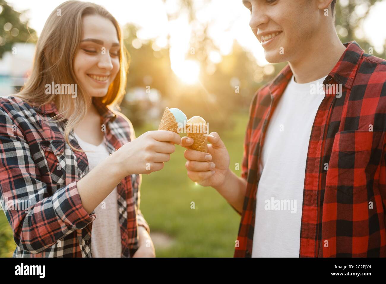 Young love couple feed each other ice cream in summer park. Boyfriend ...