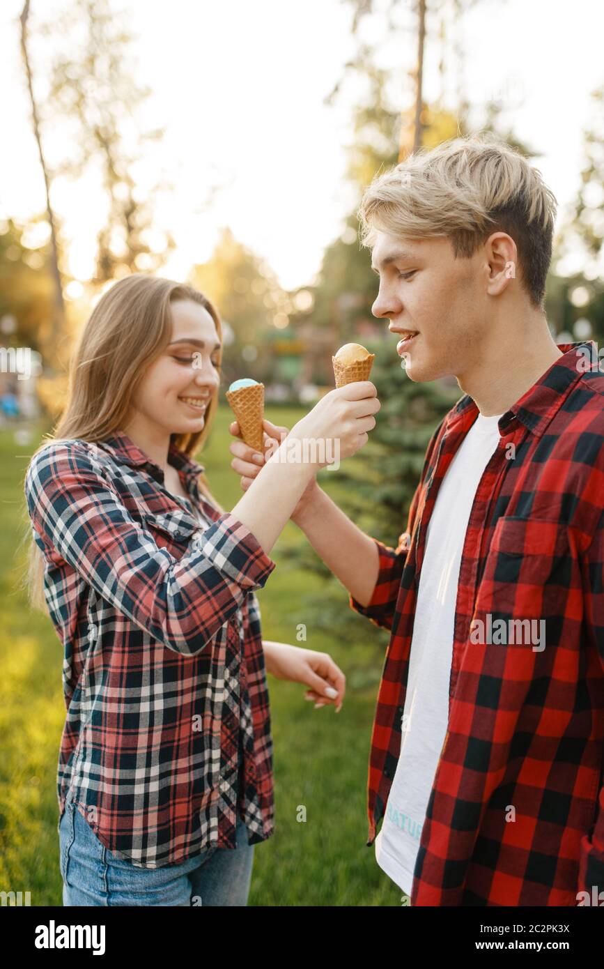 Young love couple feed each other ice cream in summer park. Boyfriend ...