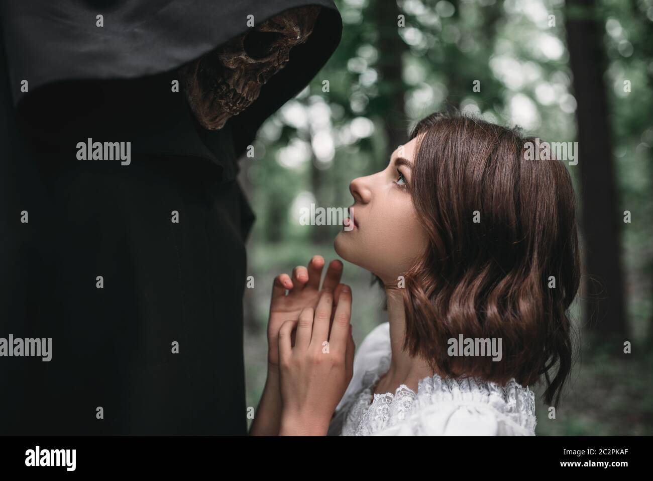 Female victim looks into the eyes of death in a black hoodie, forest on ...