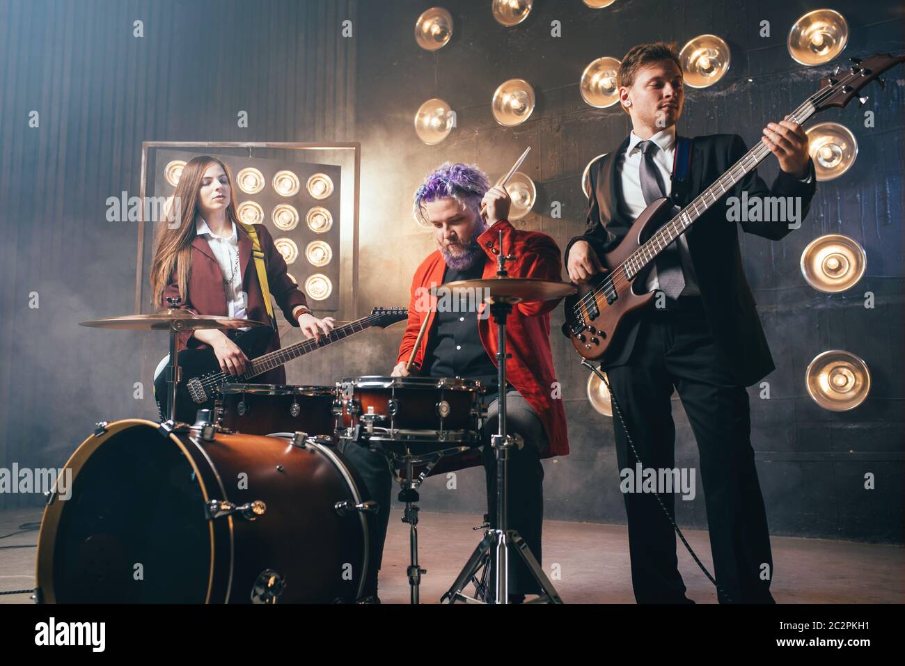 Bearded drummer in red suit, performing on the stage with lights ...