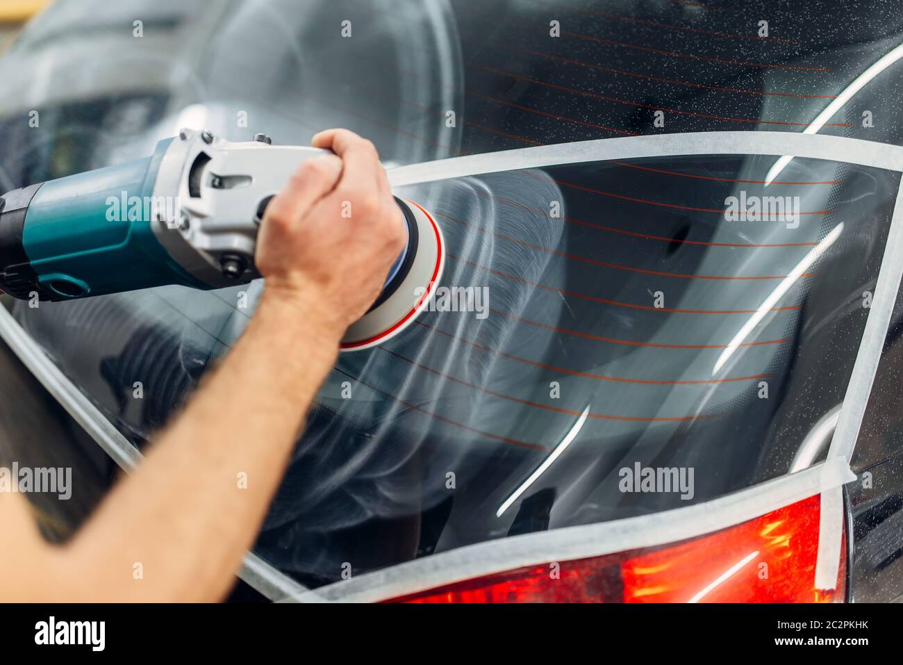 Worker with polishing machine removes the track from wiper blade on car ...