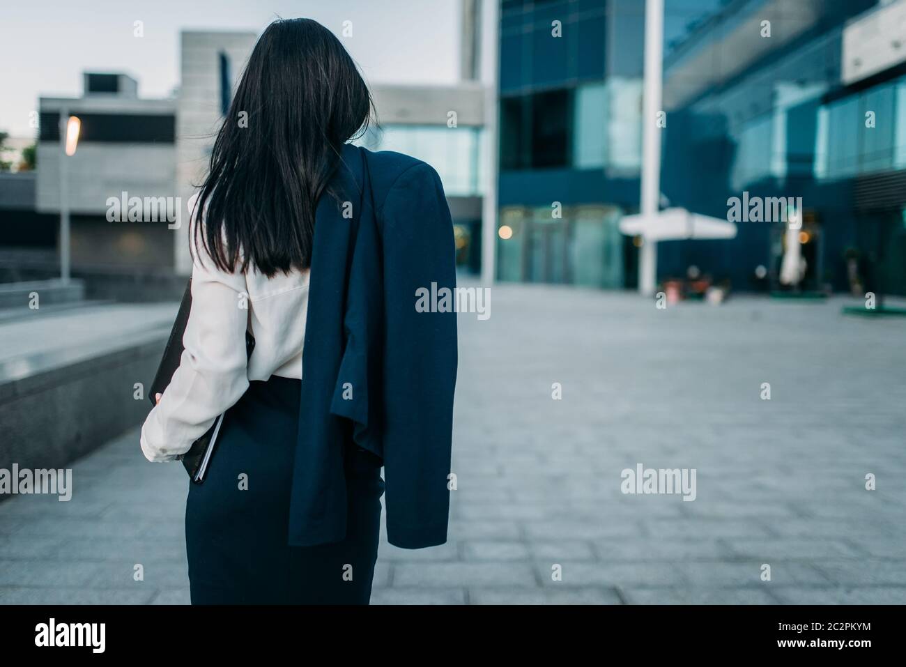 Businesswoman with suit in hand, back view. Business center on ...