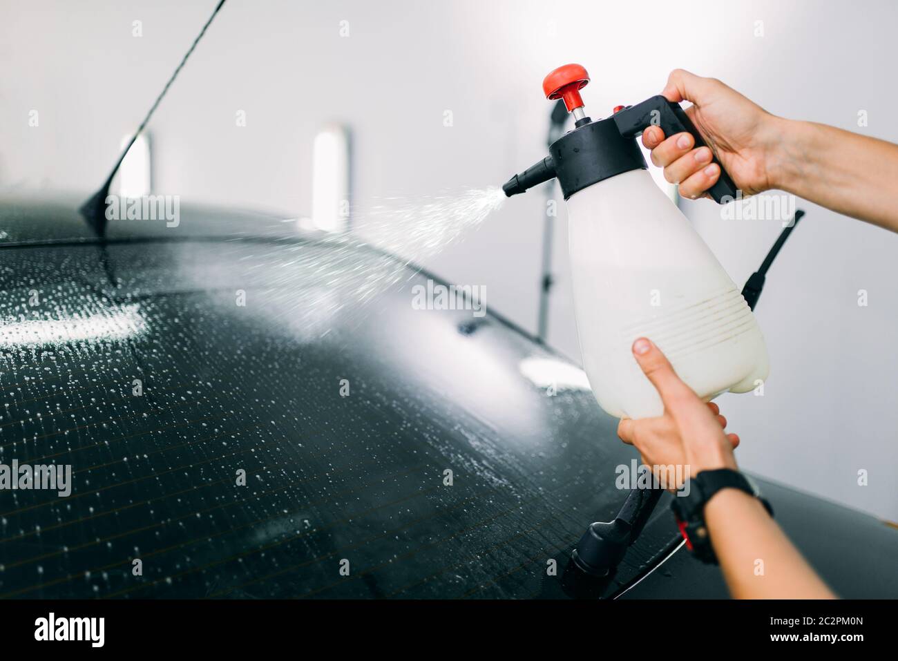 Male hand with spray, car window tint installation process, installing ...