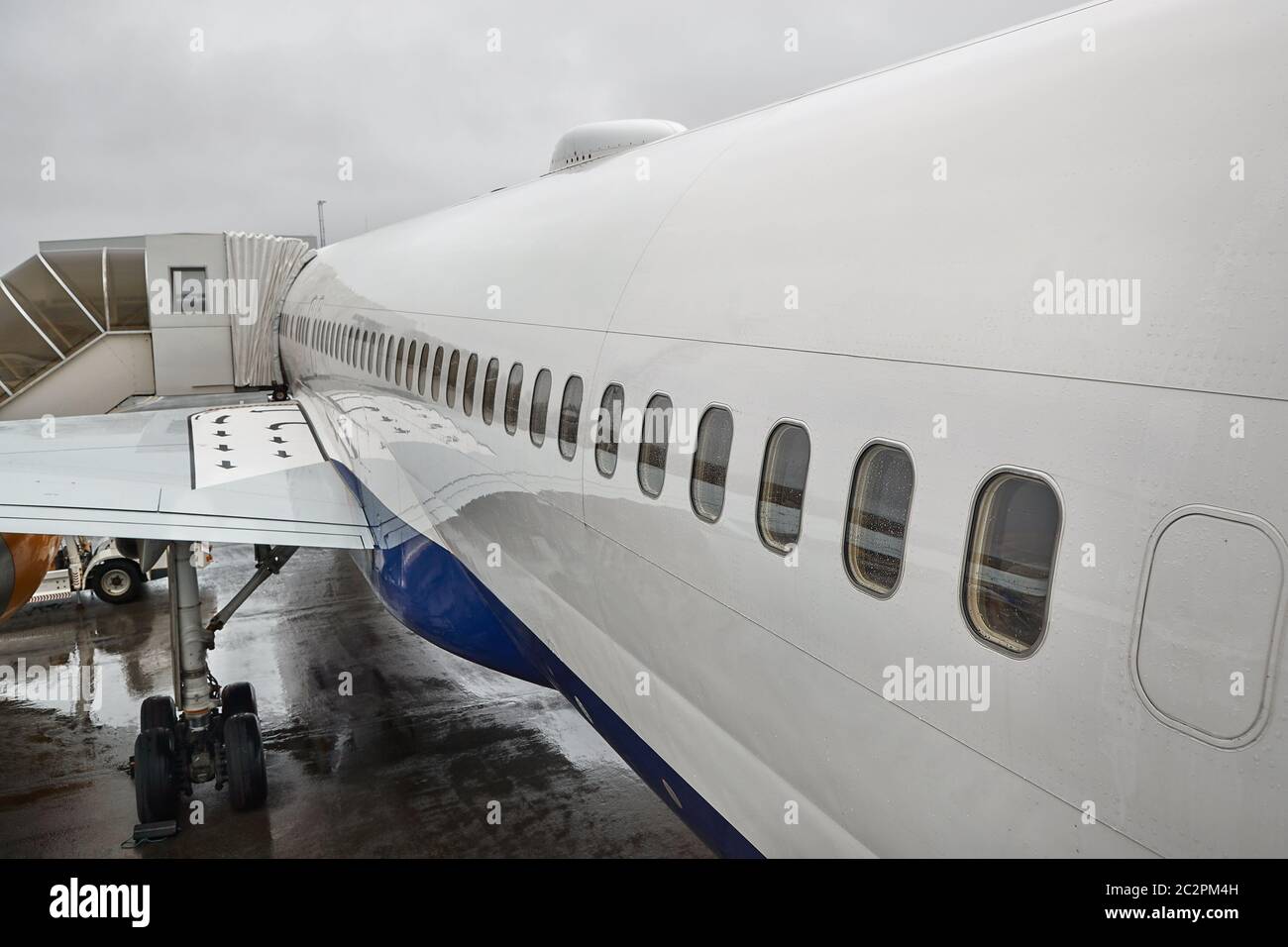Passenger aircraft fuselage detail at an airport with jet bridge ...