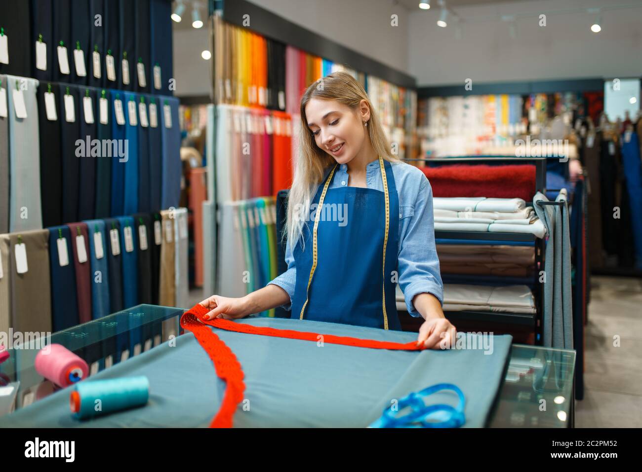 Seamstress with tape measures the fabric closeup in textile store ...