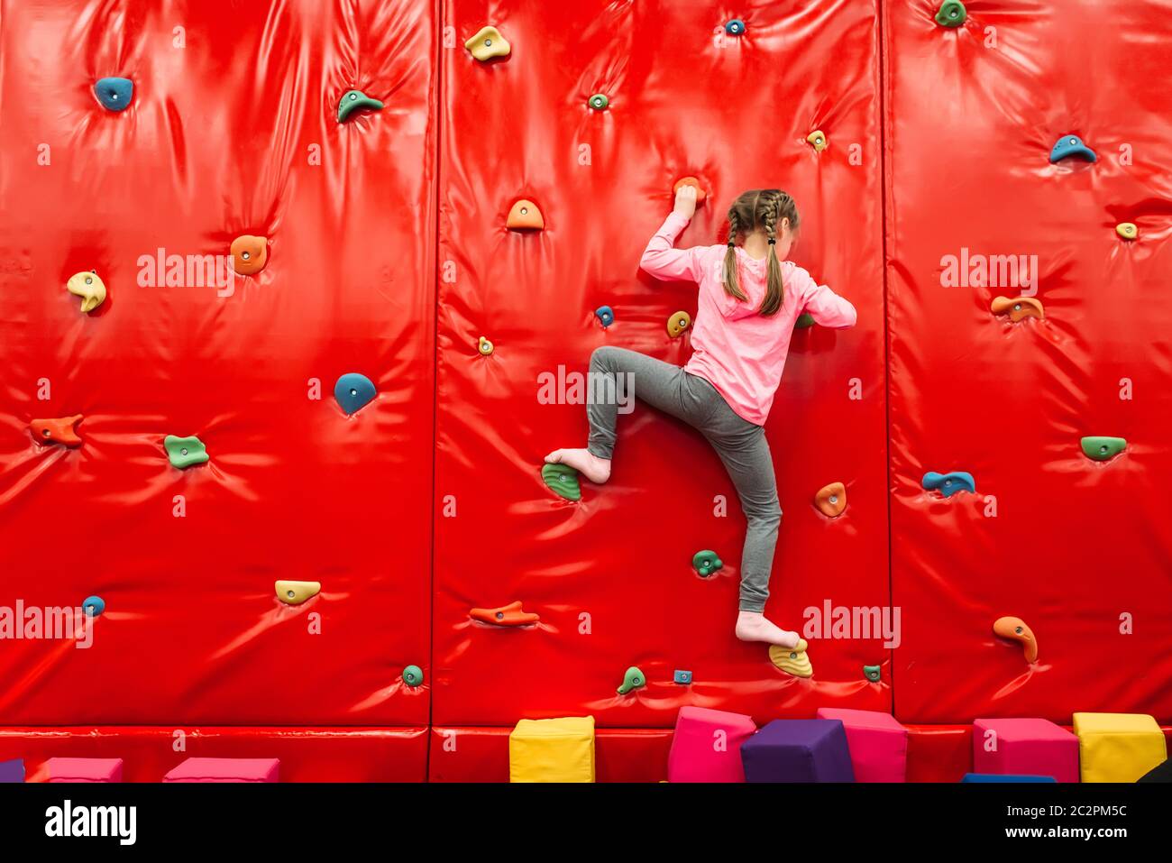 Girl climbing on a wall in childrens attraction playground ...
