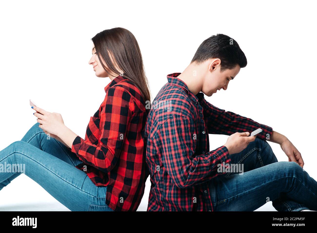 Smartphone addicted people. Couple sitting back to back and using ...