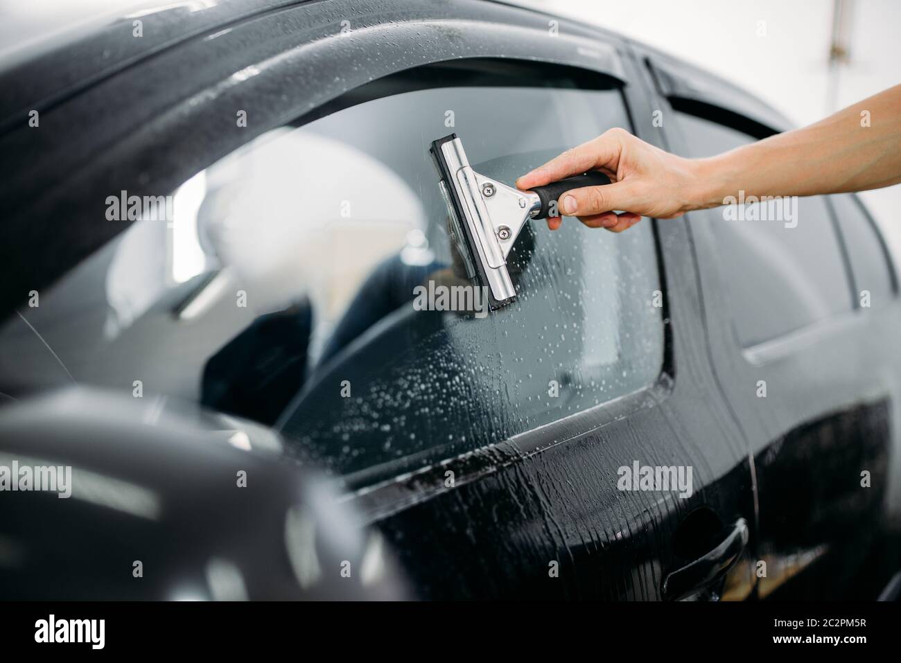 Male specialist work with car window, tinting film installation process ...