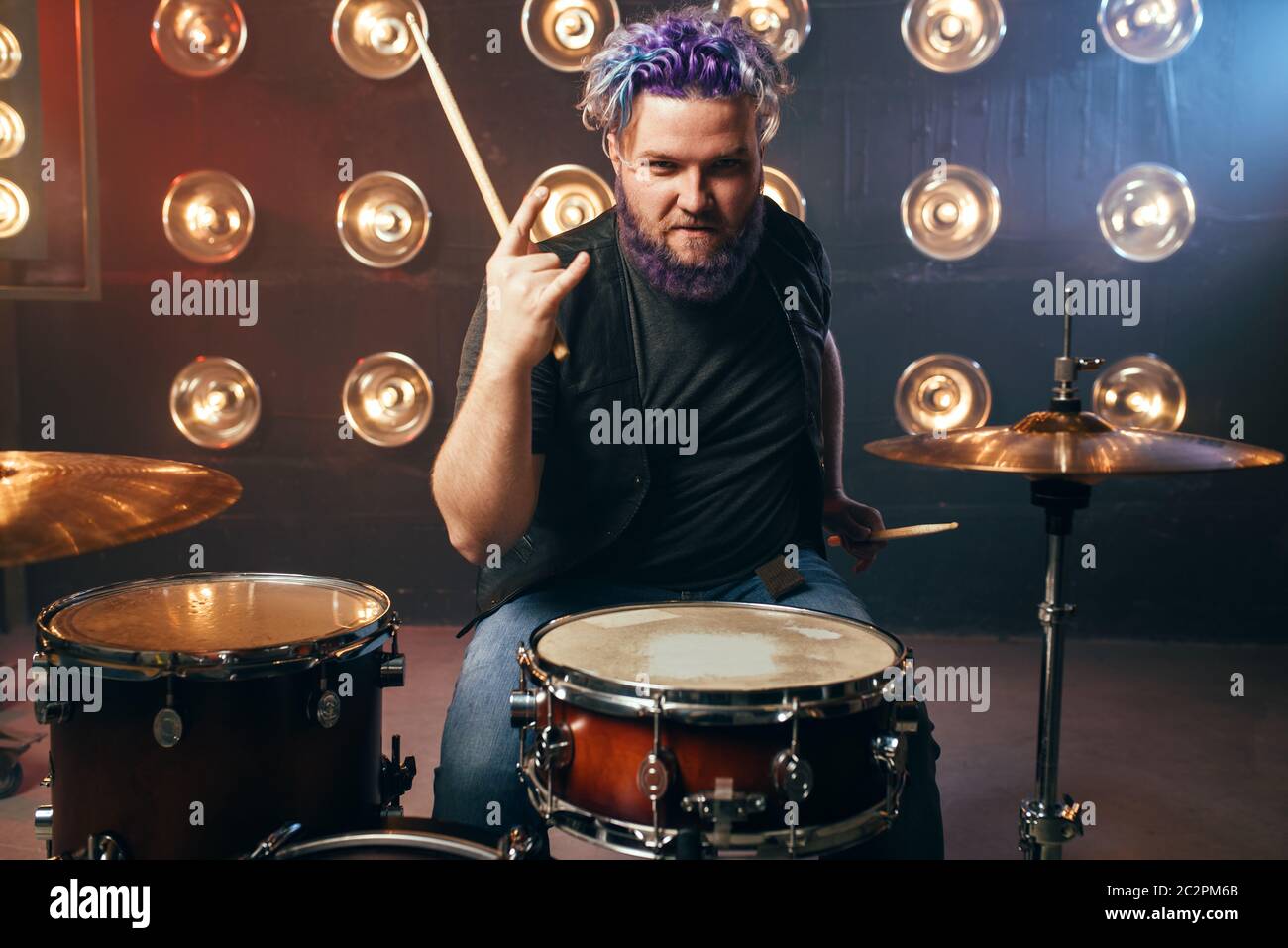 Bearded drummer with colorful hair, rock performer on the stage with ...