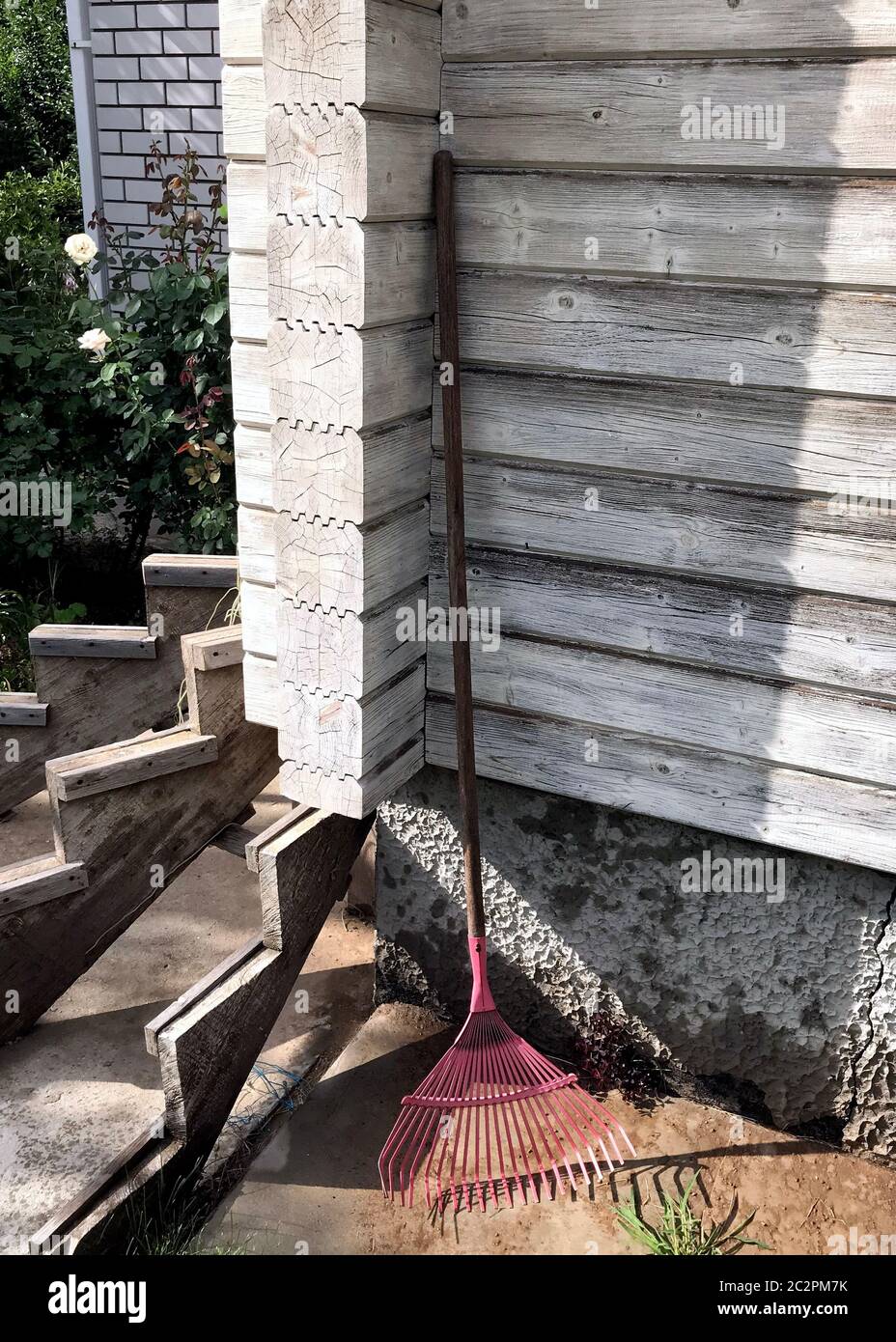 Rake by the wooden wall of the house. Garden tools Stock Photo - Alamy