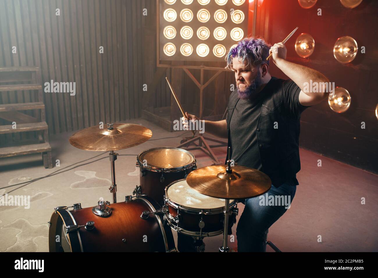 Bearded drummer with colorful hair, rock performer on the stage with ...