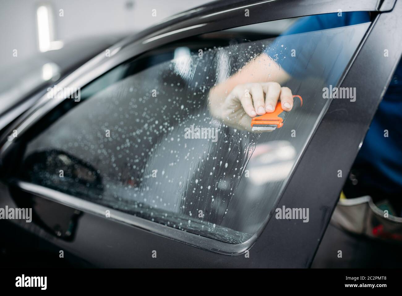 Male specialist work with car, tinting film installation process ...