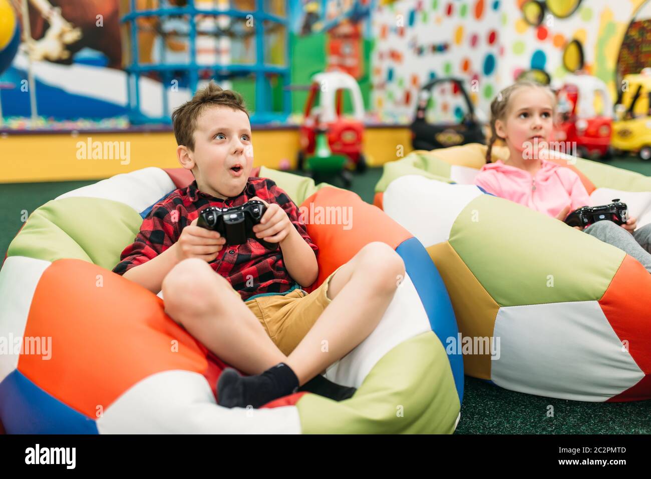 Smiling kids play in a games console in childrens entertainment center ...