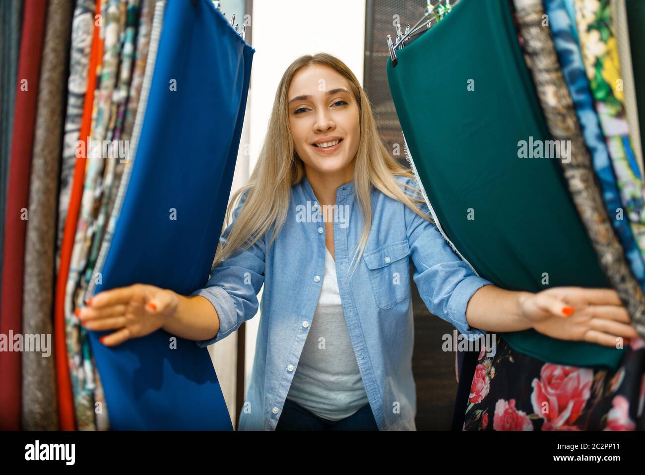 Woman between fabric in textile store. Seamstress choosing material for ...