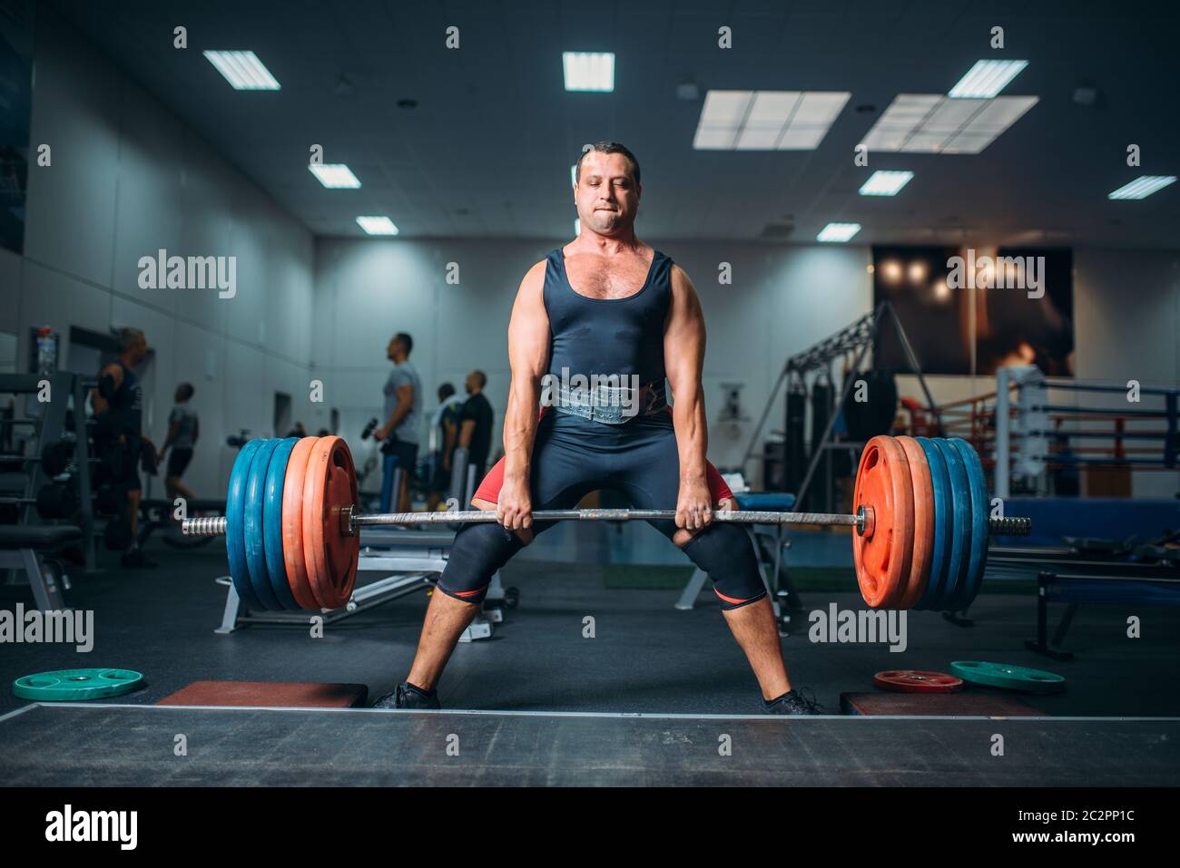 Strong weightlifter doing exercise with barbell, deadlift, gym interior ...