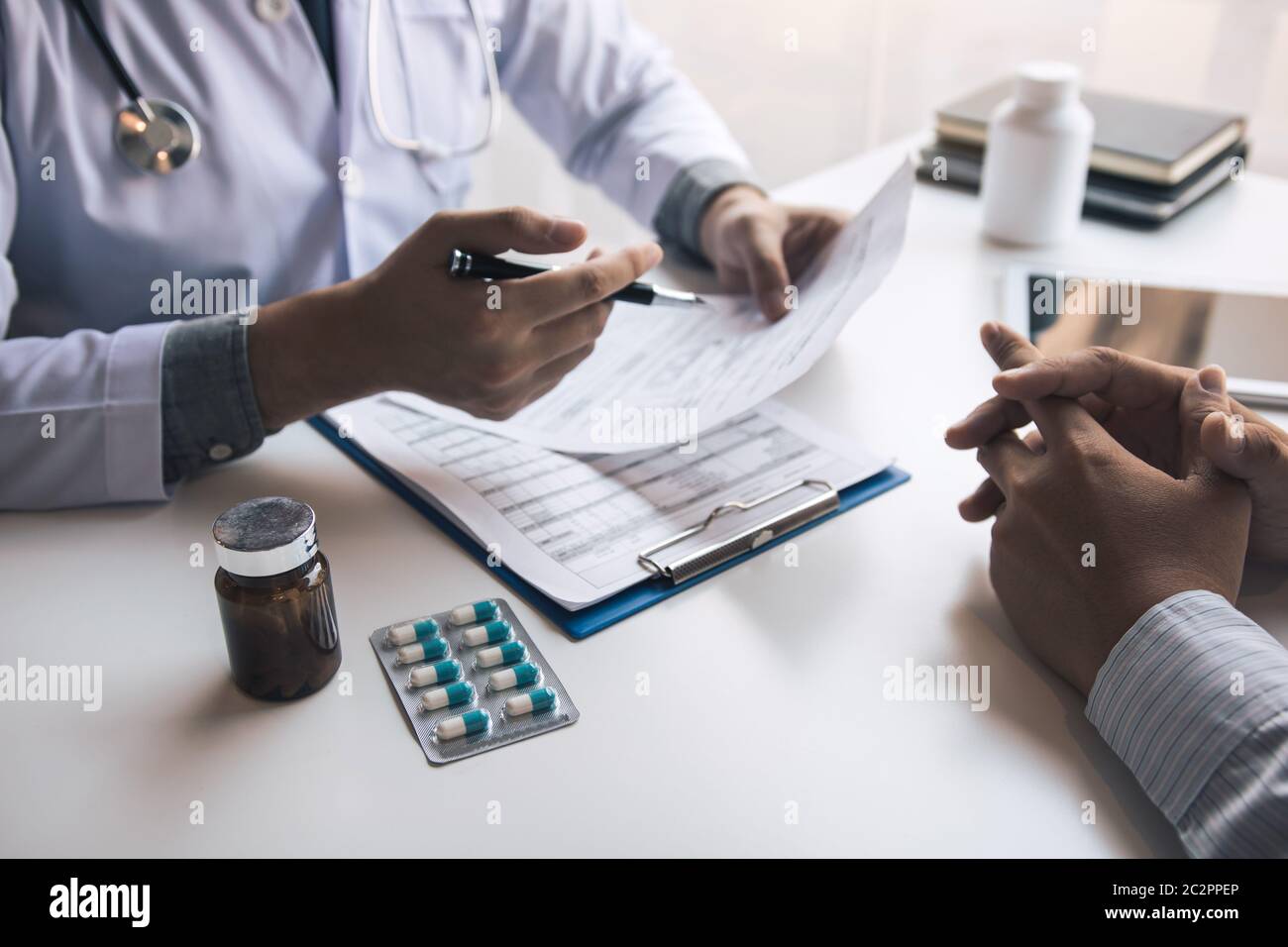 Doctor hand holding pen writing patient history list on note pad and ...