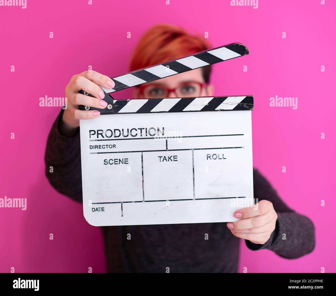 redhead woman holding movie clapper on pink background Stock Photo - Alamy