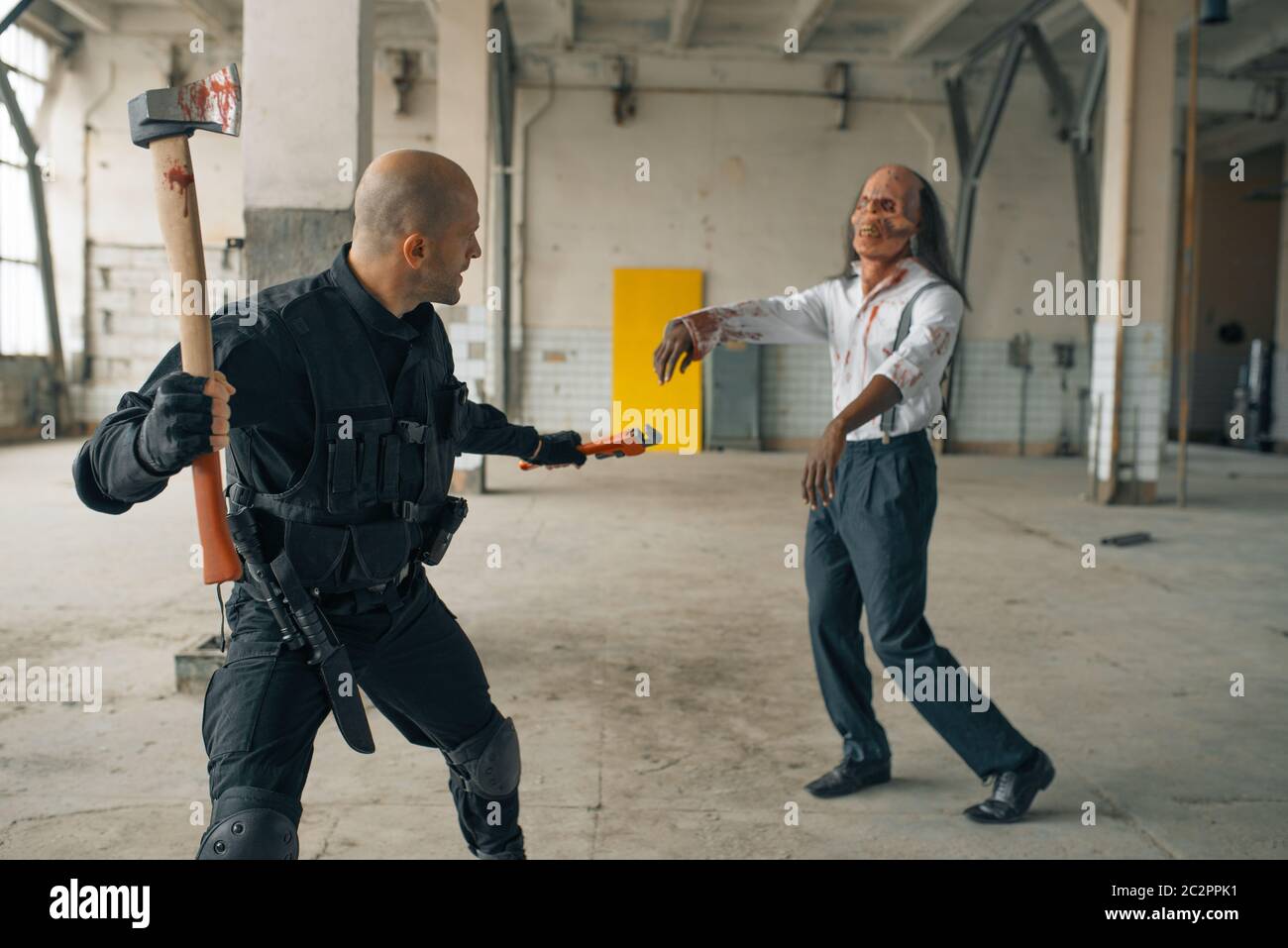 Military man with axe, battle with zombie in abandoned factory. Horror ...
