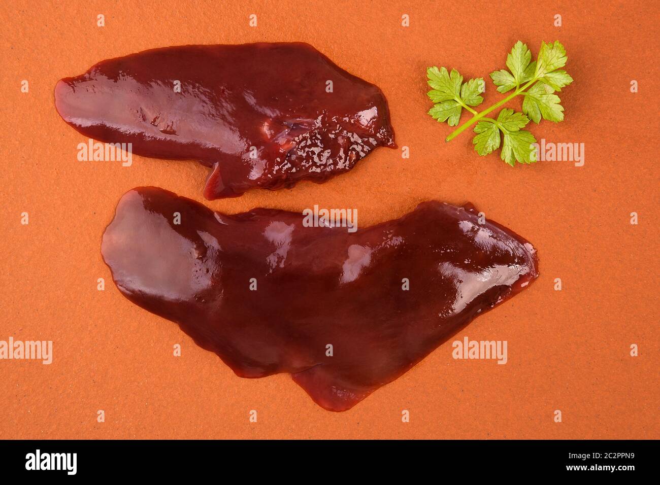 Raw rabbit liver on orange background garnished with herb parsley. Food ...