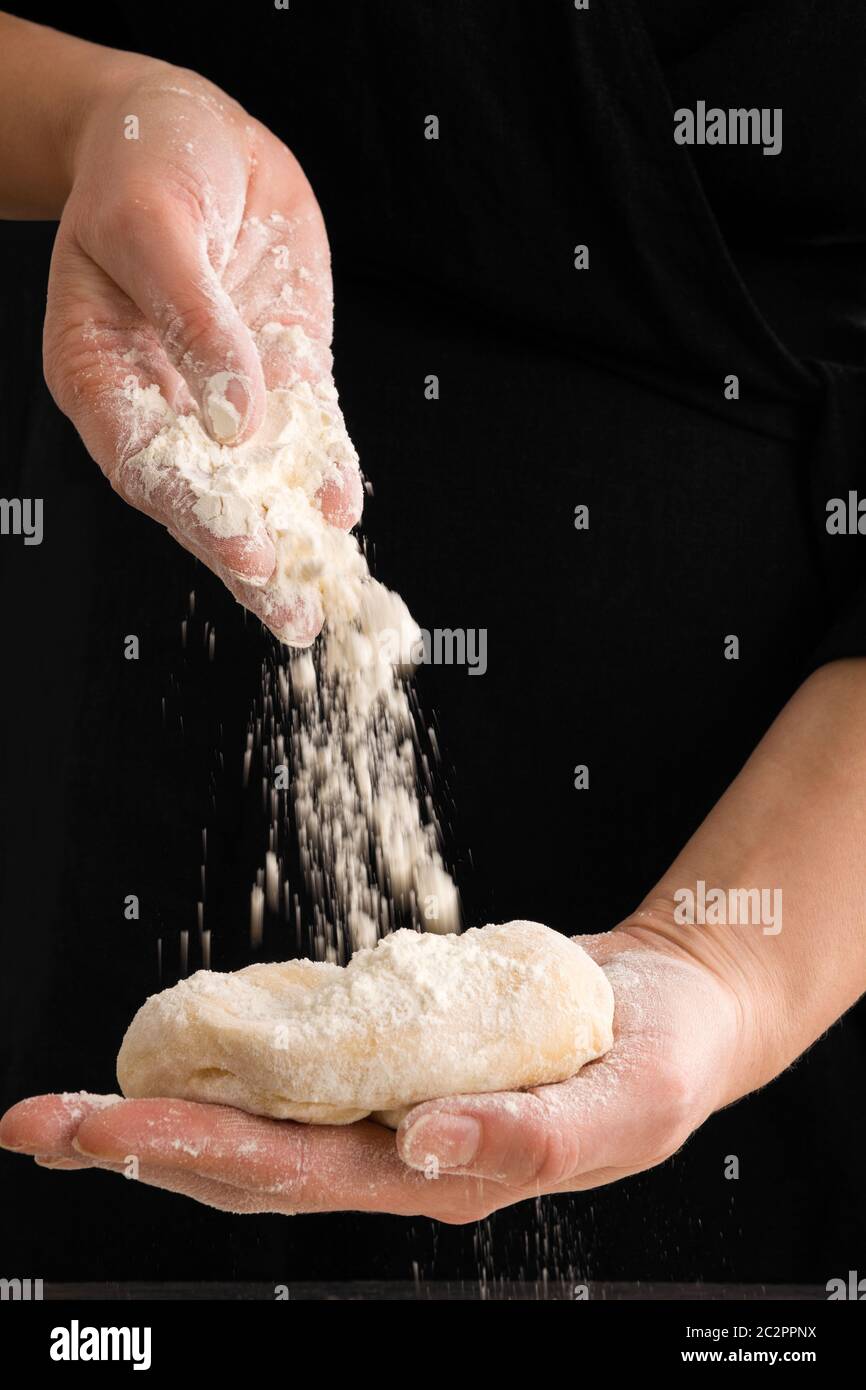 White flour falling on dough in female hands. Cooking and kitchen ...