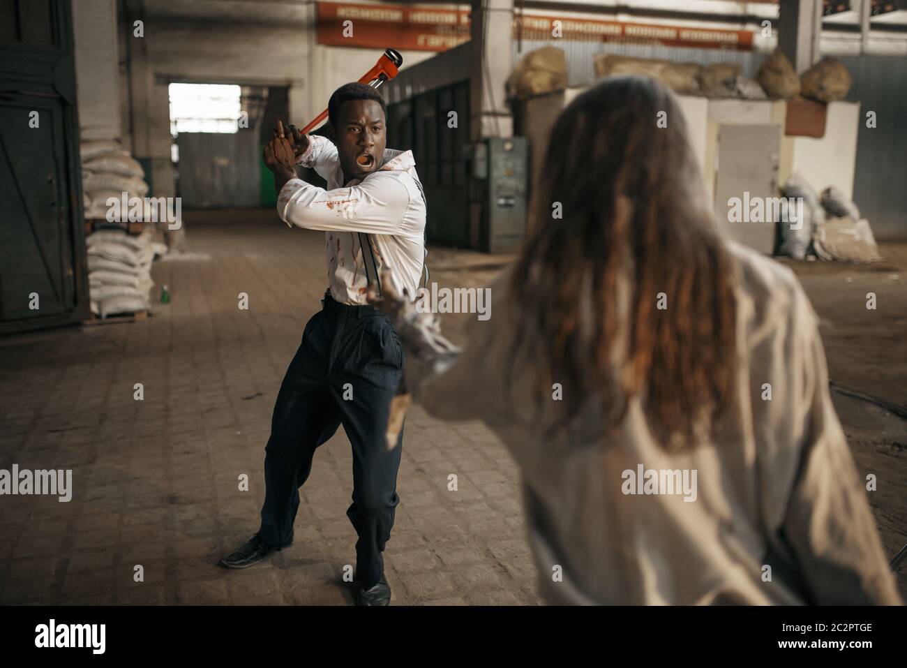 Female zombie fights with hopeless man in abandoned factory. Horror in ...