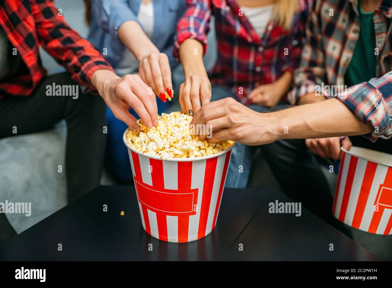 Group of people eating popcorn and having fun in cinema hall before the ...