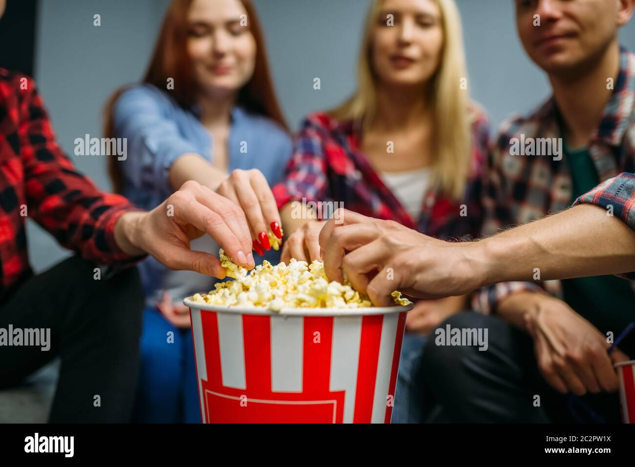 Group of people eating popcorn and having fun in cinema hall before the ...