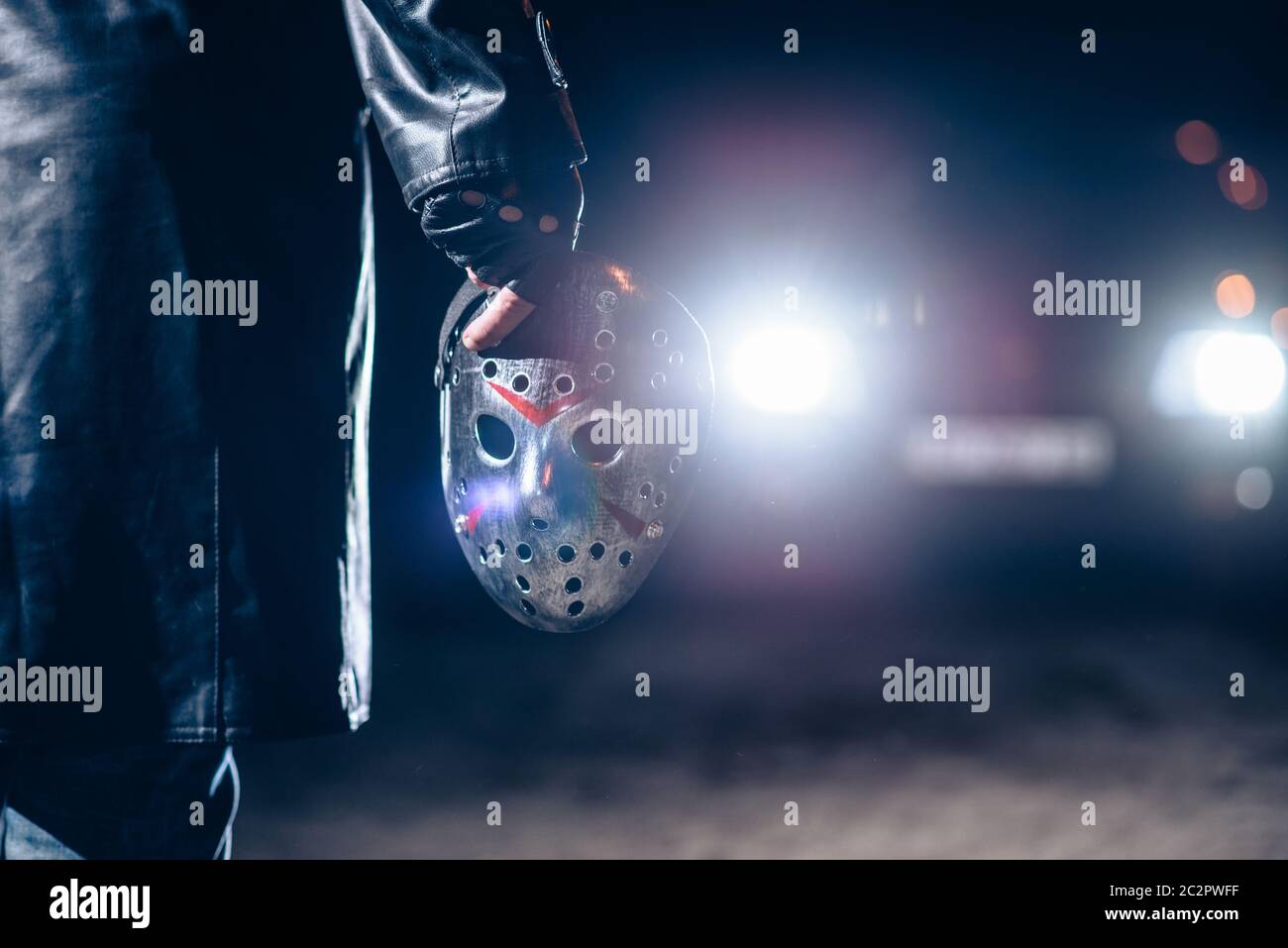 Serial maniac hand with bloody hockey mask closeup, car light at the ...
