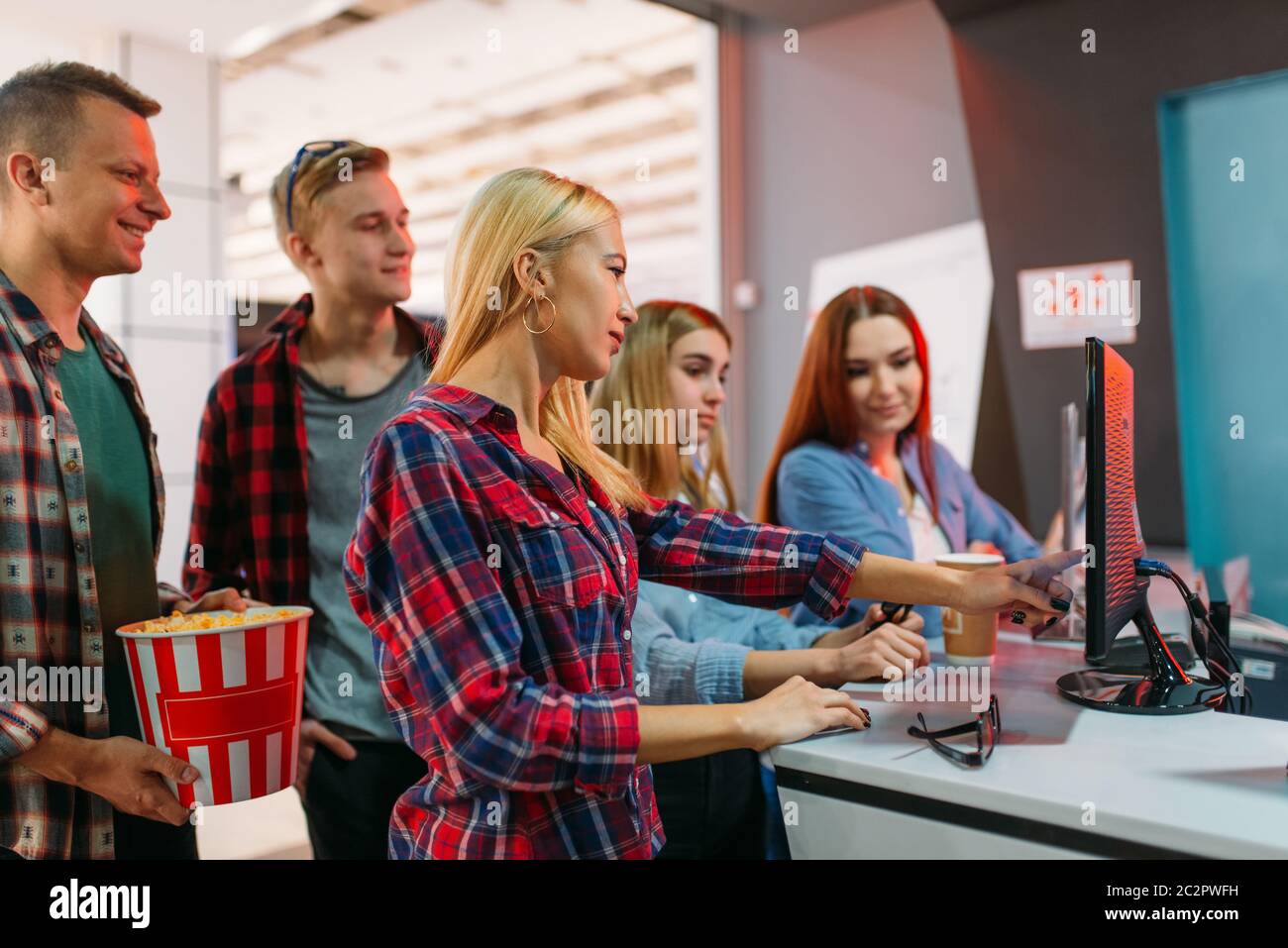 Group of friends choosing movie in cinema box office. Male and female ...