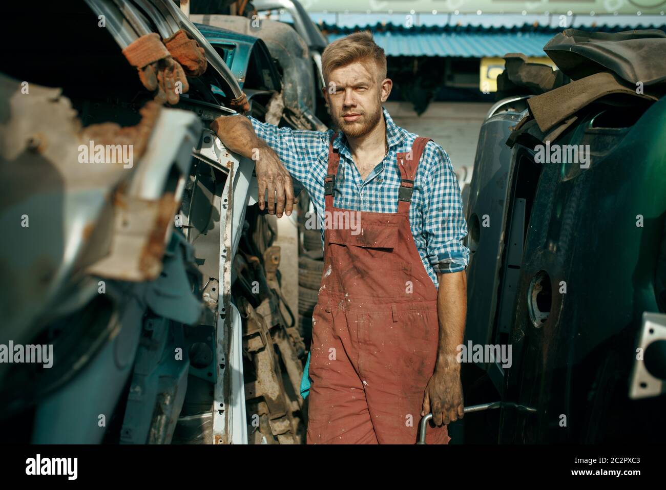 Male repairman poses on car junkyard. Auto scrap, vehicle junk ...
