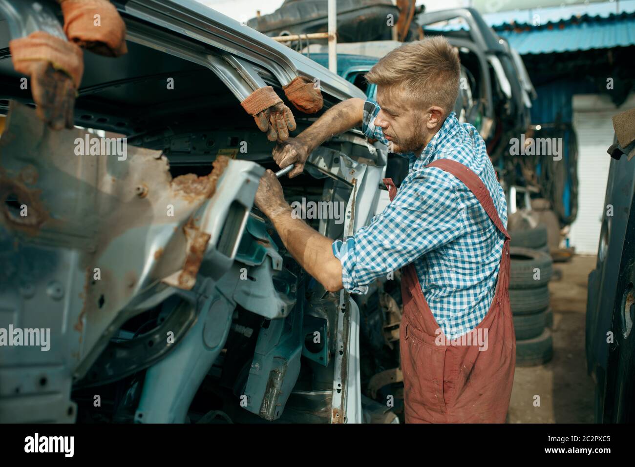 Male repairman poses on car junkyard. Auto scrap, vehicle junk ...