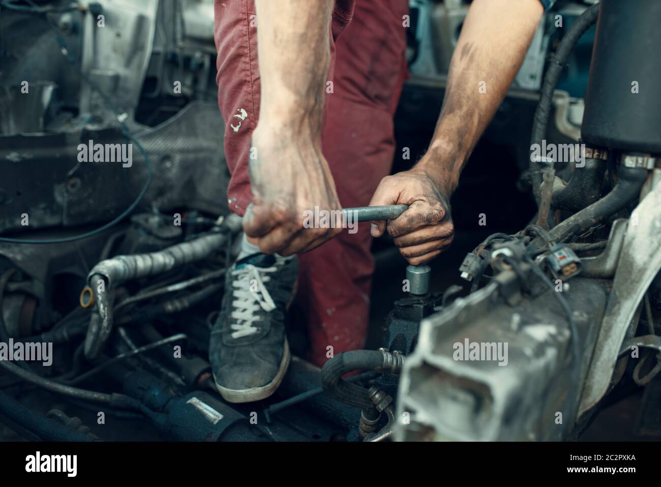 Male repairman tries to unscrew the part on car junkyard. Auto scrap ...