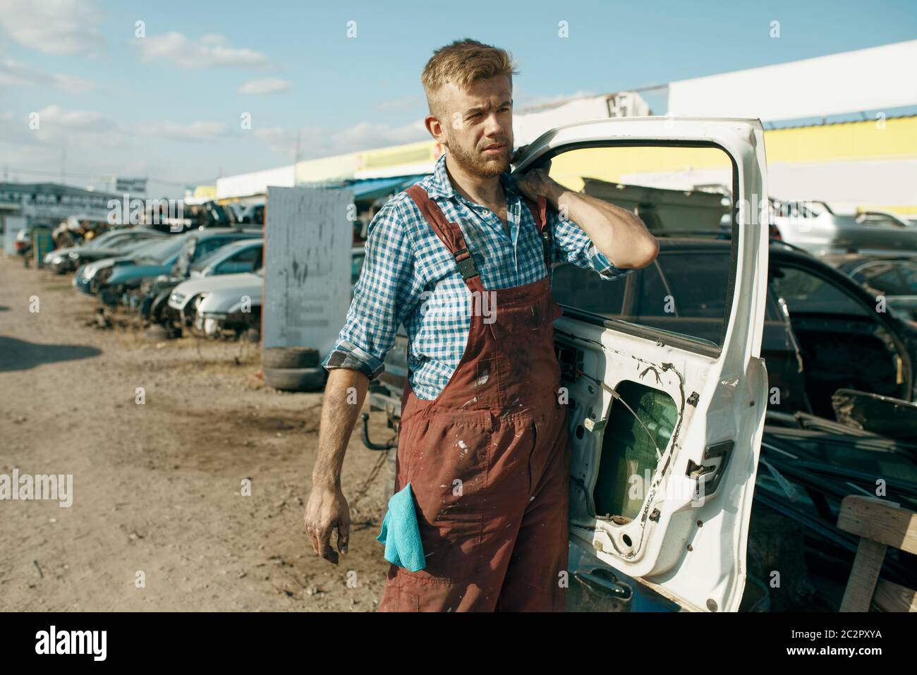 Male repairman holds door on car junkyard. Auto scrap, vehicle junk ...
