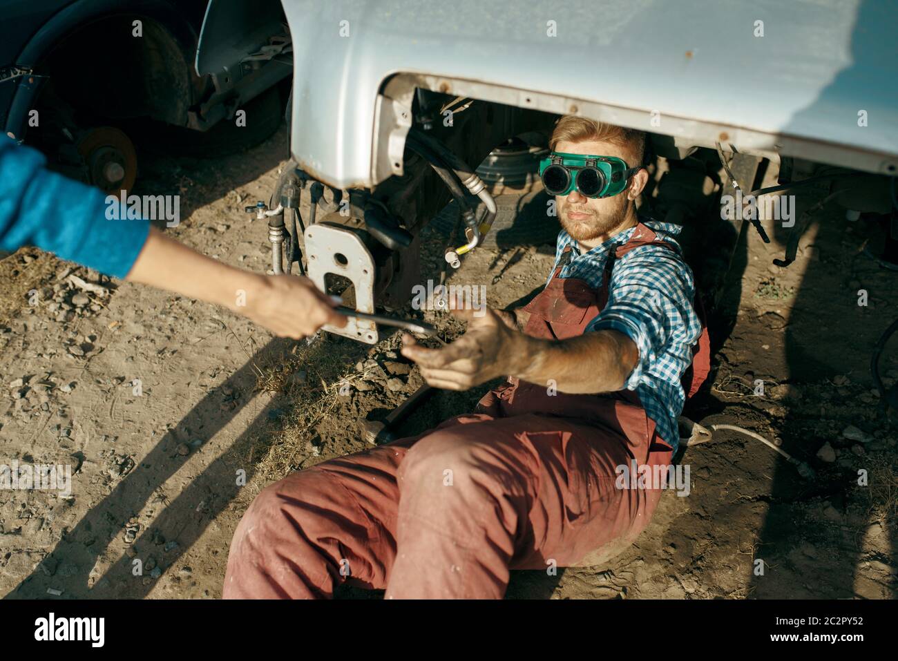 Male mechanic in welding glasses on car junkyard. Auto scrap, vehicle ...