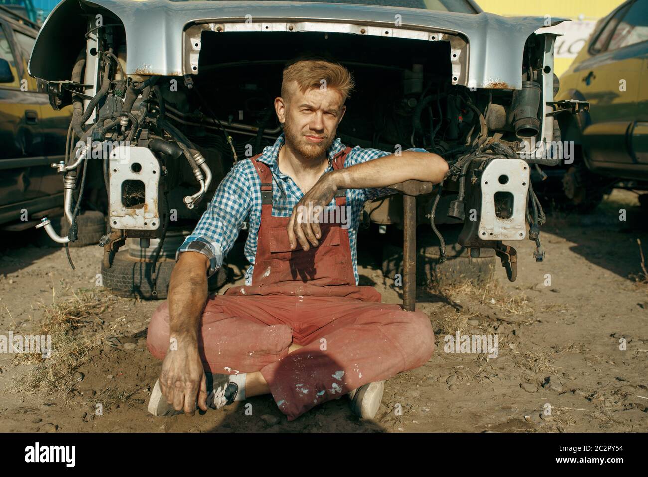 Male mechanic poses on car junkyard. Auto scrap, vehicle junk ...