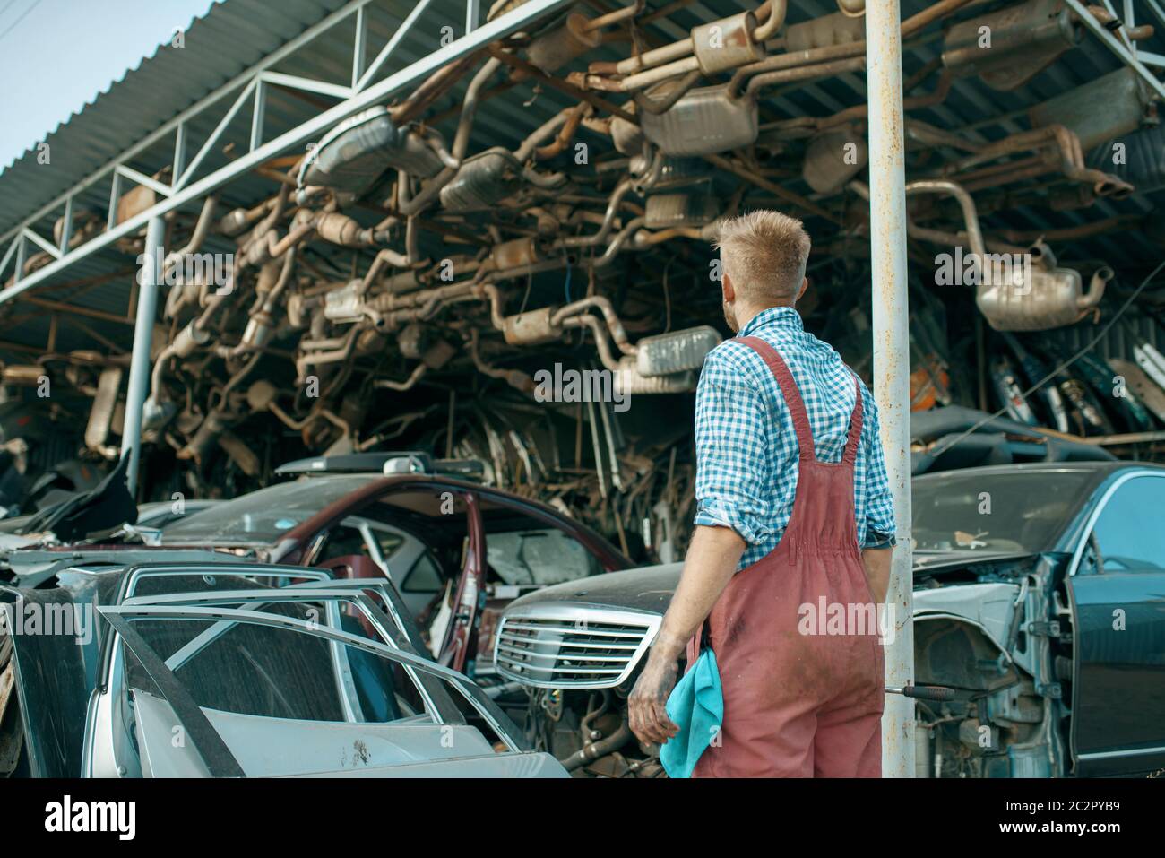 Male mechanic at the stack of cars on junkyard. Auto scrap, vehicle ...