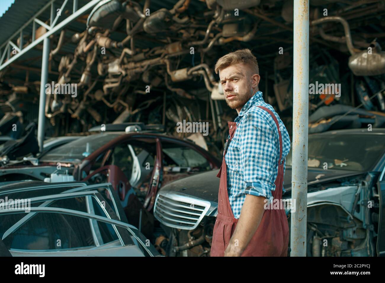 Male mechanic at the stack of cars on junkyard. Auto scrap, vehicle ...