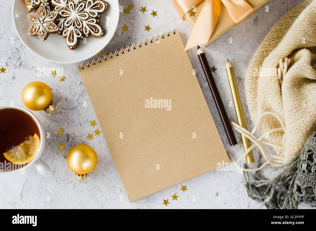 Christmas background with blank brown notebook with gift box, tea, gingerbread cookies and plaid ...