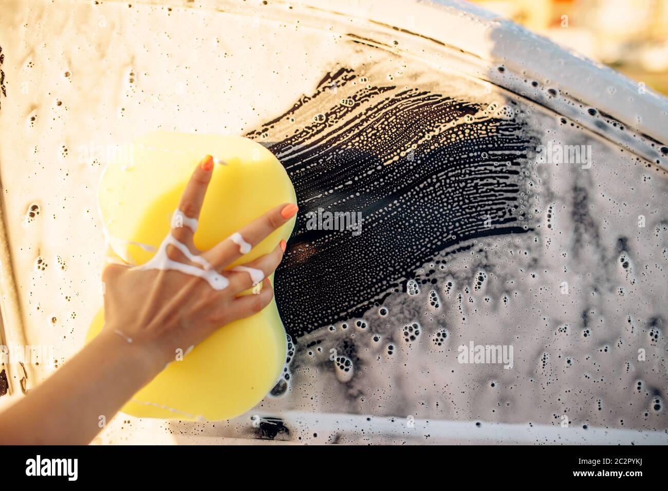 Female person hand with sponge scrubbing vehicle with foam, car wash ...