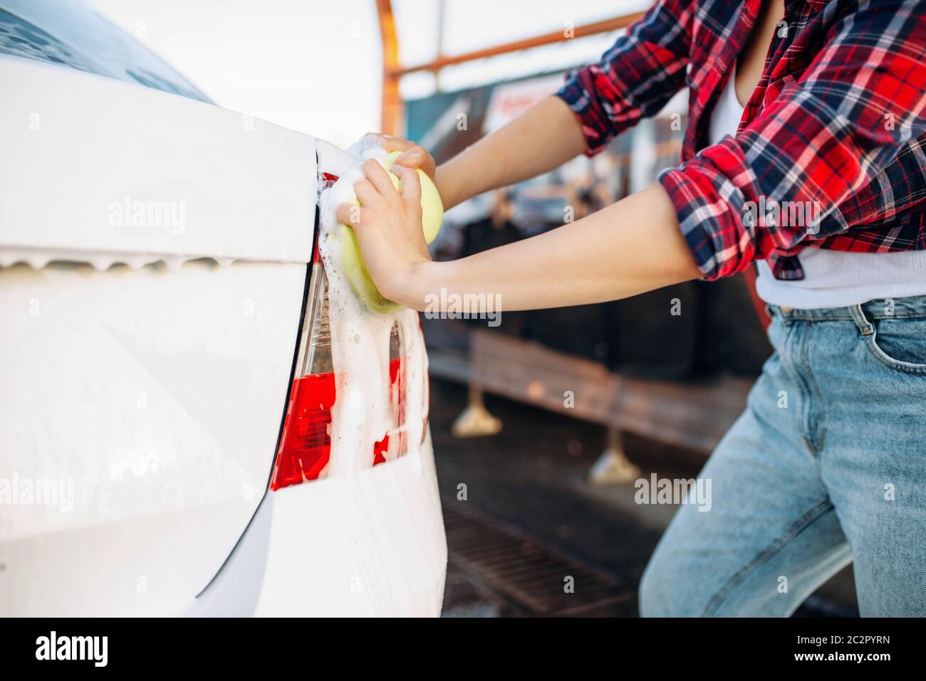Female person with sponge scrubbing vehicle rear lights with foam, car ...
