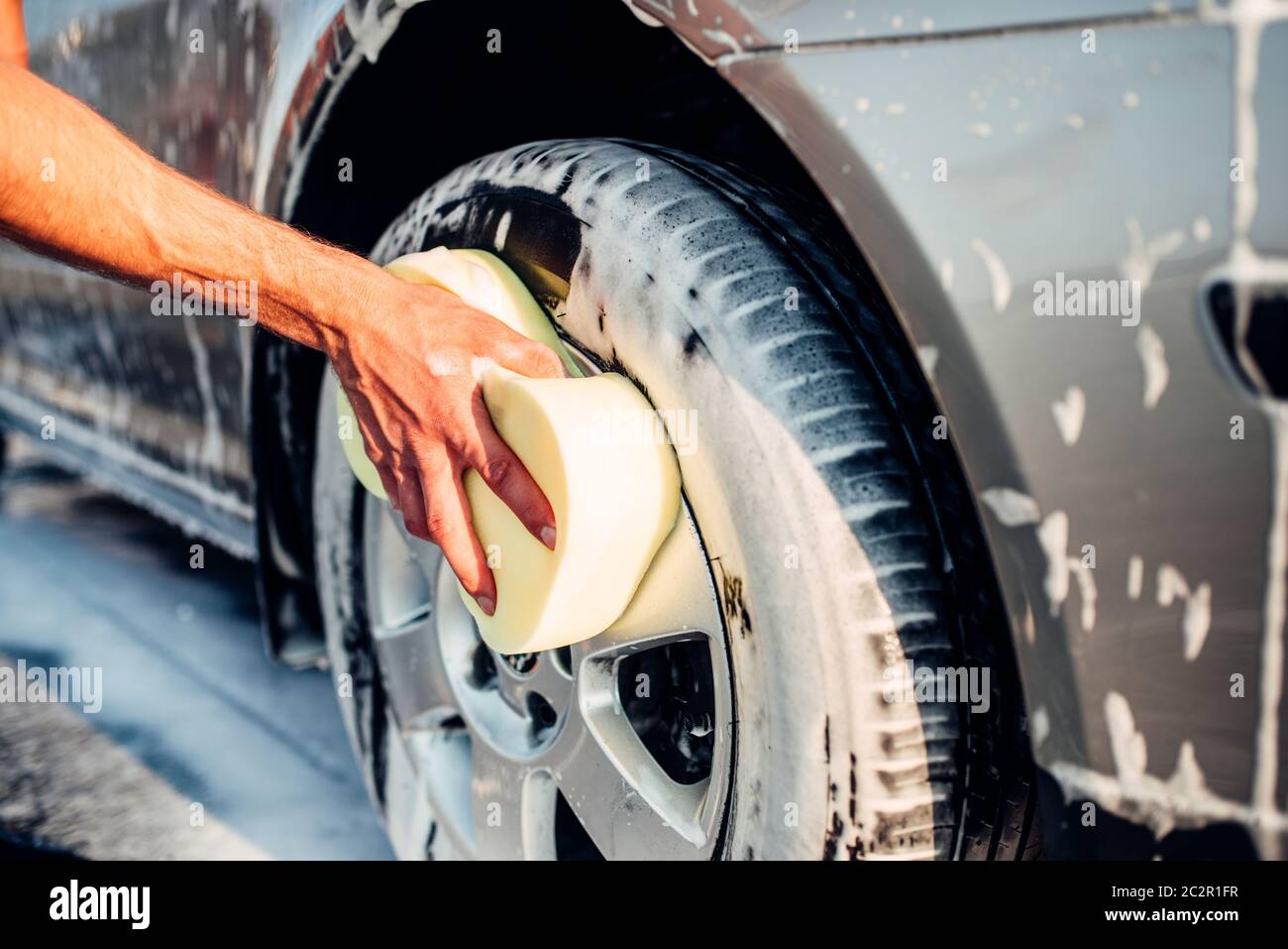 Male hand rubbing car wheel with foam, automobile in suds. Carwash ...