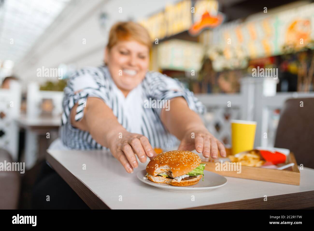 Fat woman eating high calorie food in mall restaurant. Overweight ...