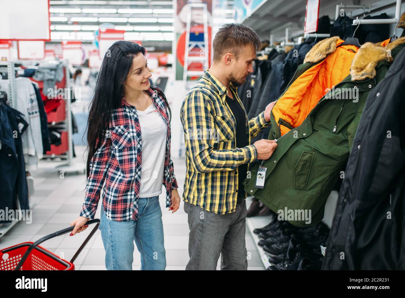 Young couple choosing warm clothes in supermarket. Male and female ...