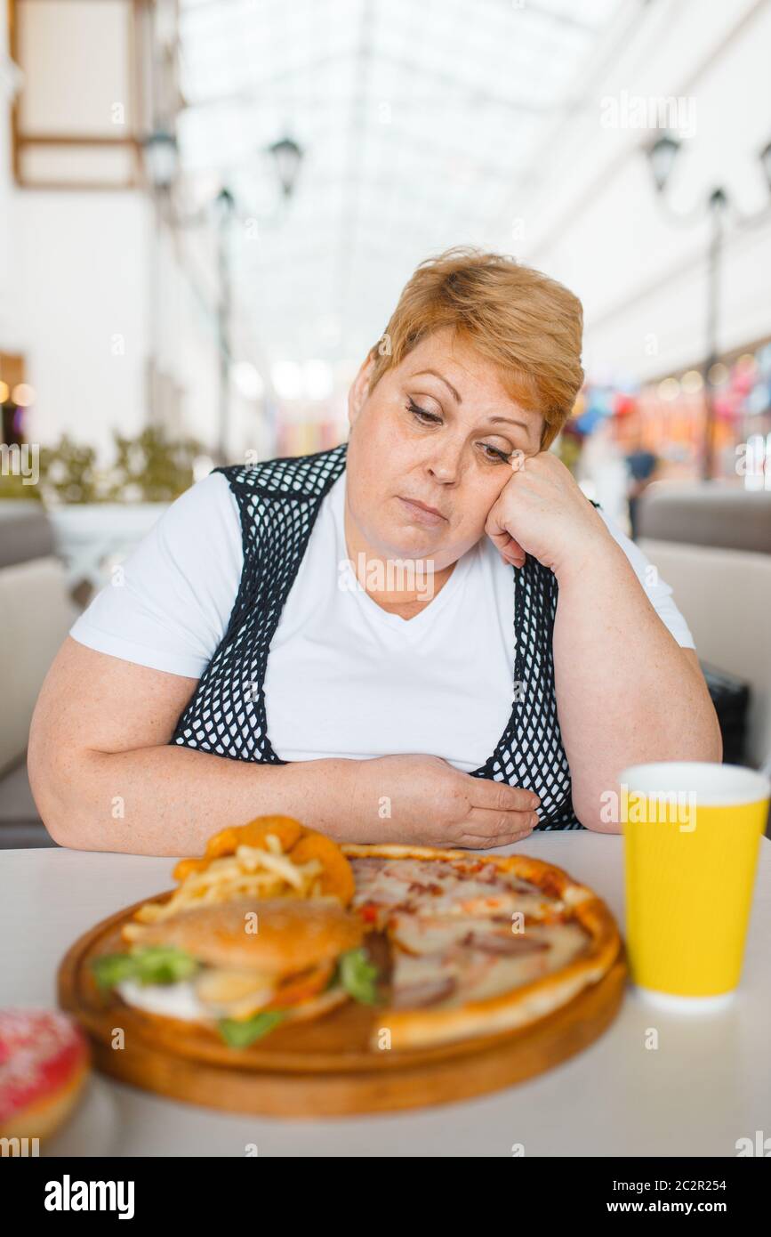 Fatty woman eating pizza in fastfood restaurant, unhealthy food ...