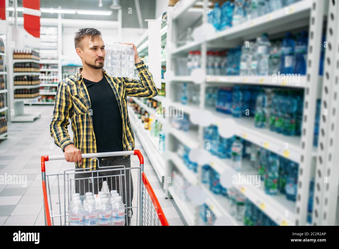 Young man buying mineral water in supermarket. Male customer on ...
