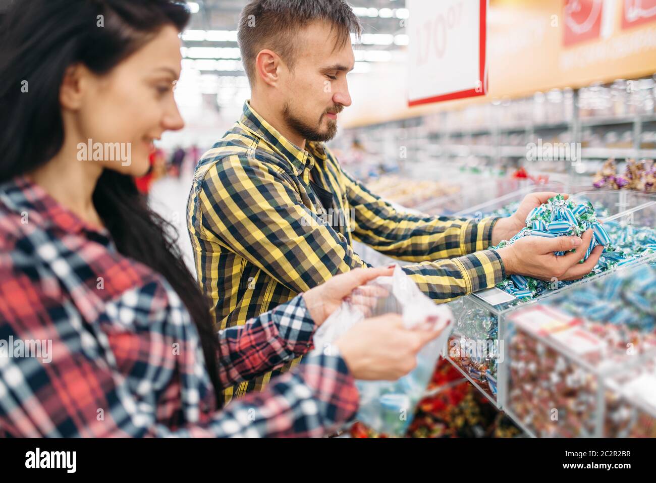 Happy couple buying sweets and candies in supermarket. Male and female ...