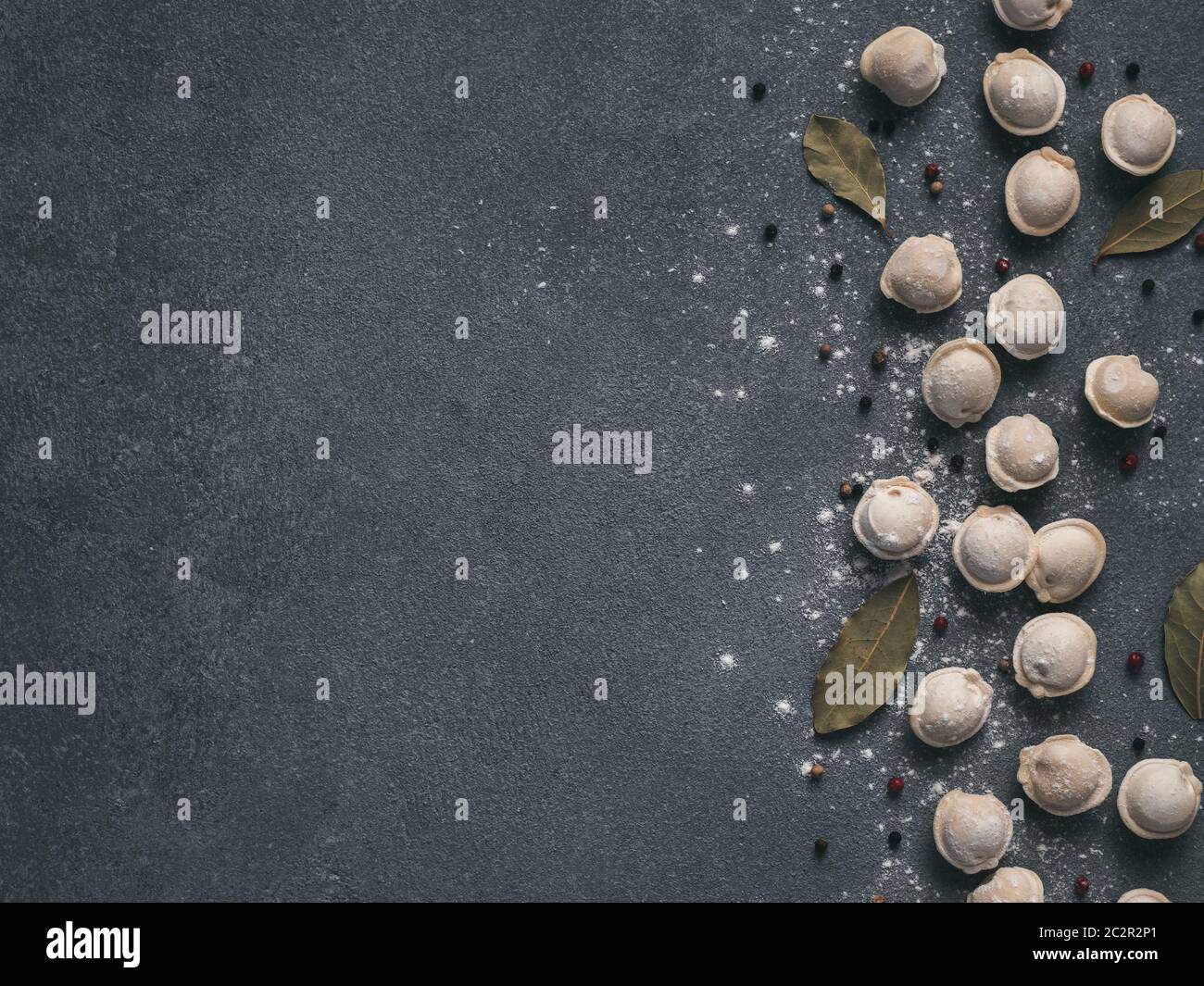 Pattern of frozen uncooked russian pelmeni with peppercorns and bay ...