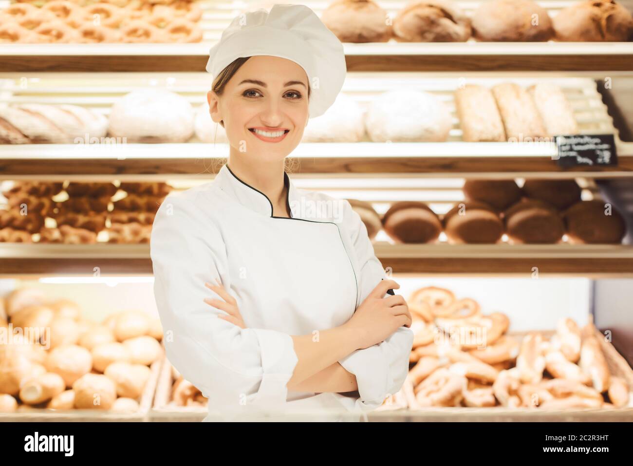 Sales woman in bakery shop standing in front of delicious bread in a ...